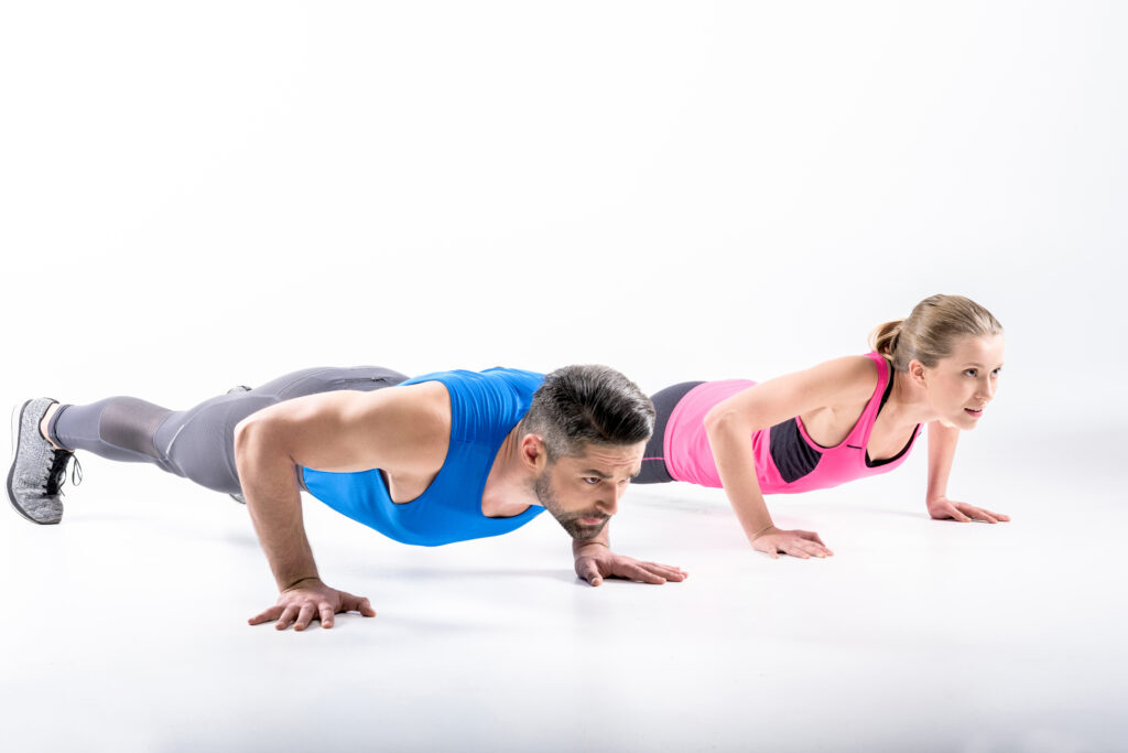 Young sporty couple doing push ups together - Hybrid Fitness